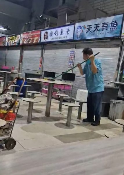Stallholder cleans tables with 'broom' at Yuhua Hawker Centre ...
